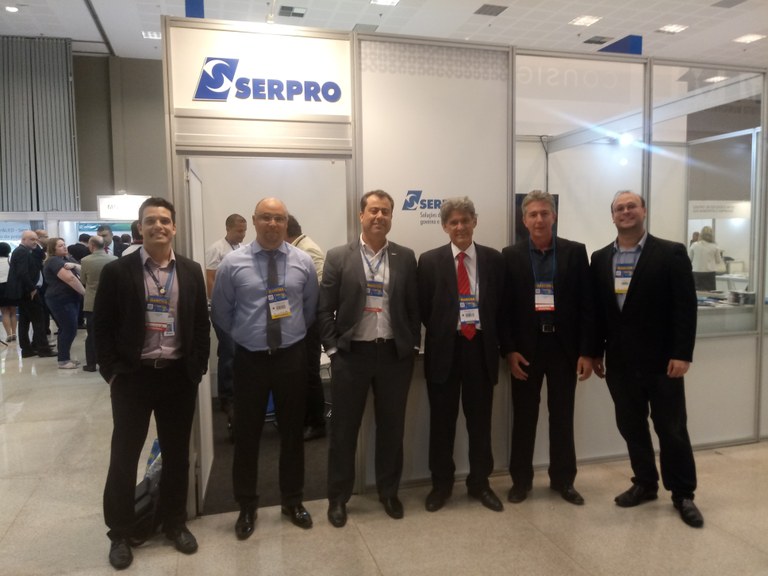 Seis profissionais do Serpro estão em pé, em frente ao estado do Serpro